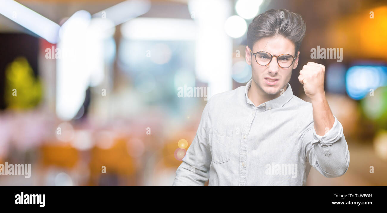 Young handsome man wearing glasses over isolated background angry and ...