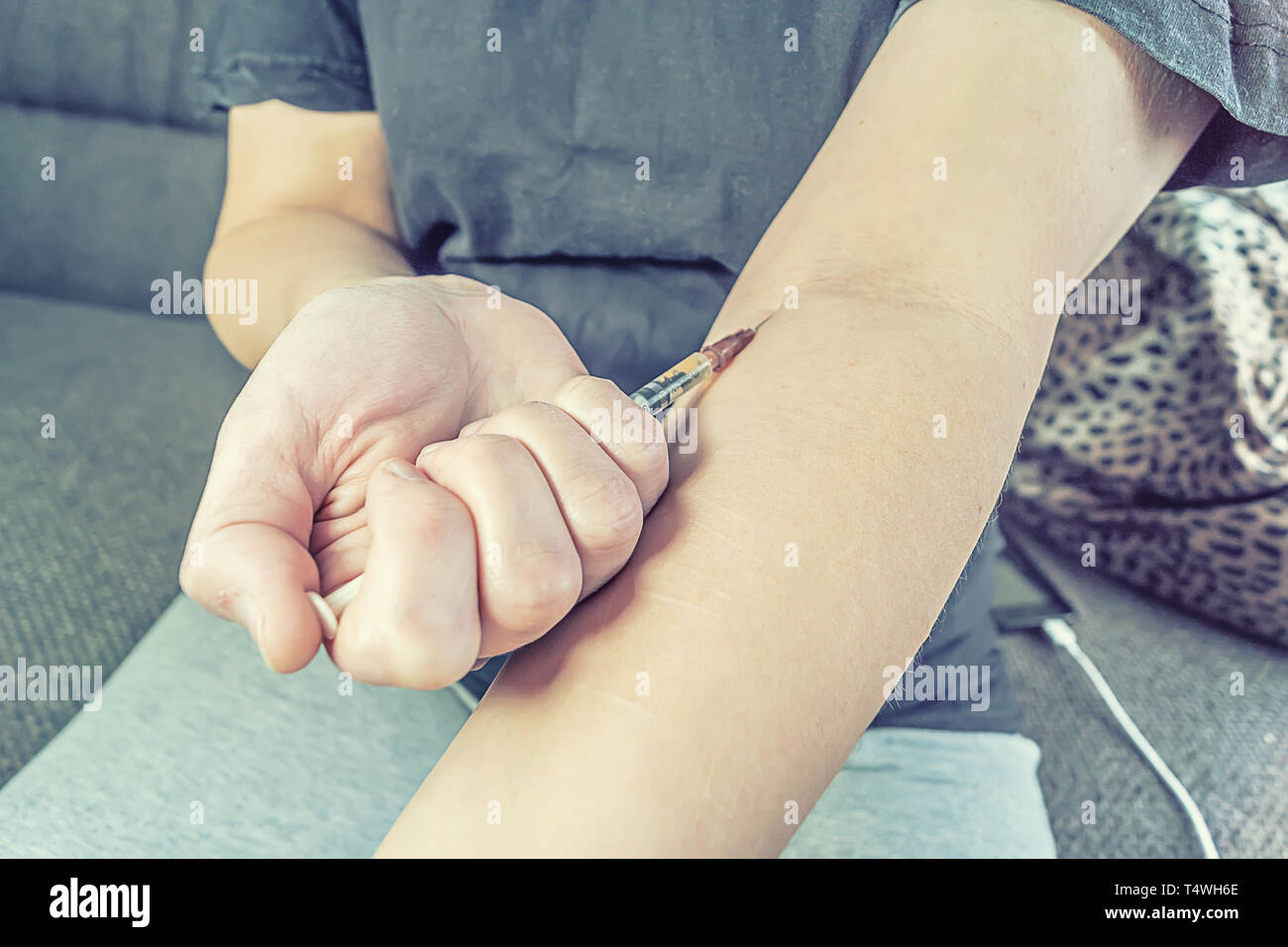 young drug addict with a syringe in her hand makes herself an injection ...