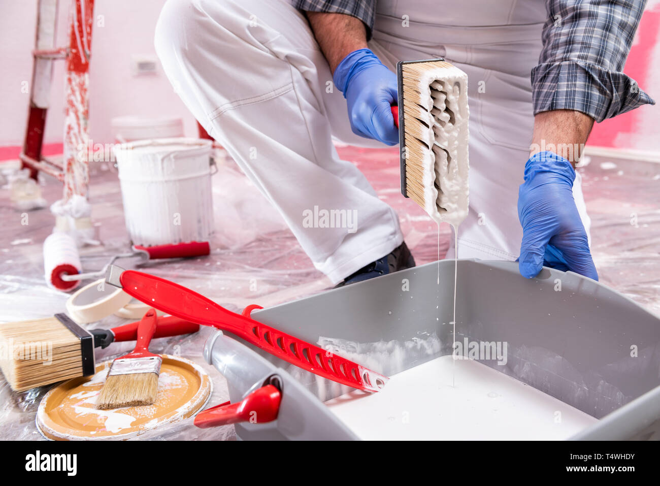 Caucasian house painter worker in white overalls, prepare the white ...
