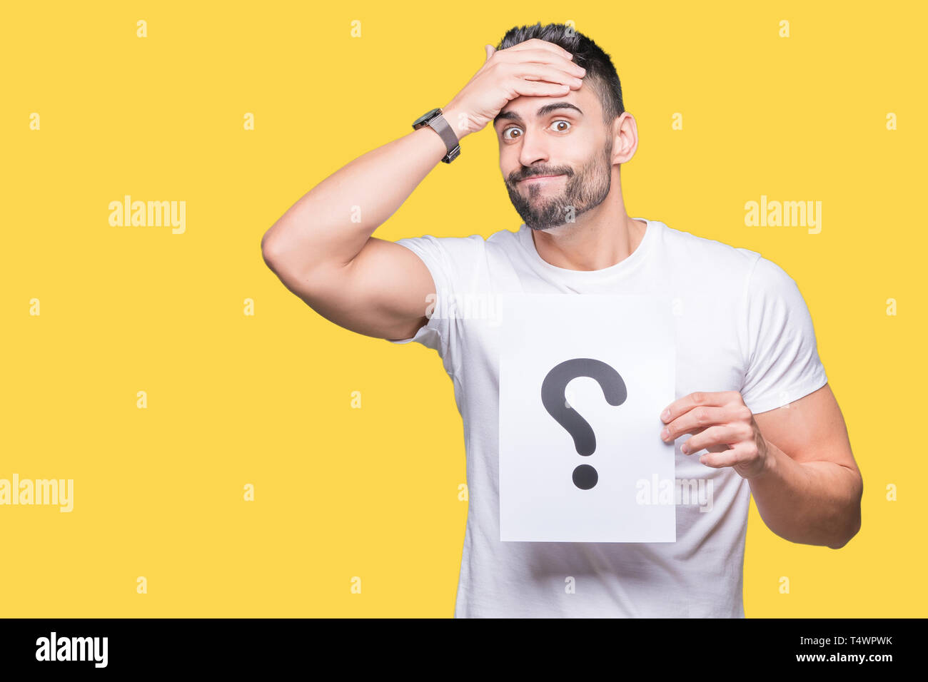 Handsome young man holding paper with question mark over isolated ...