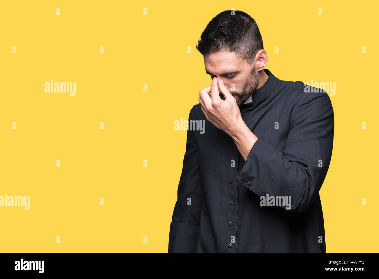 Young Christian priest over isolated background tired rubbing nose and ...