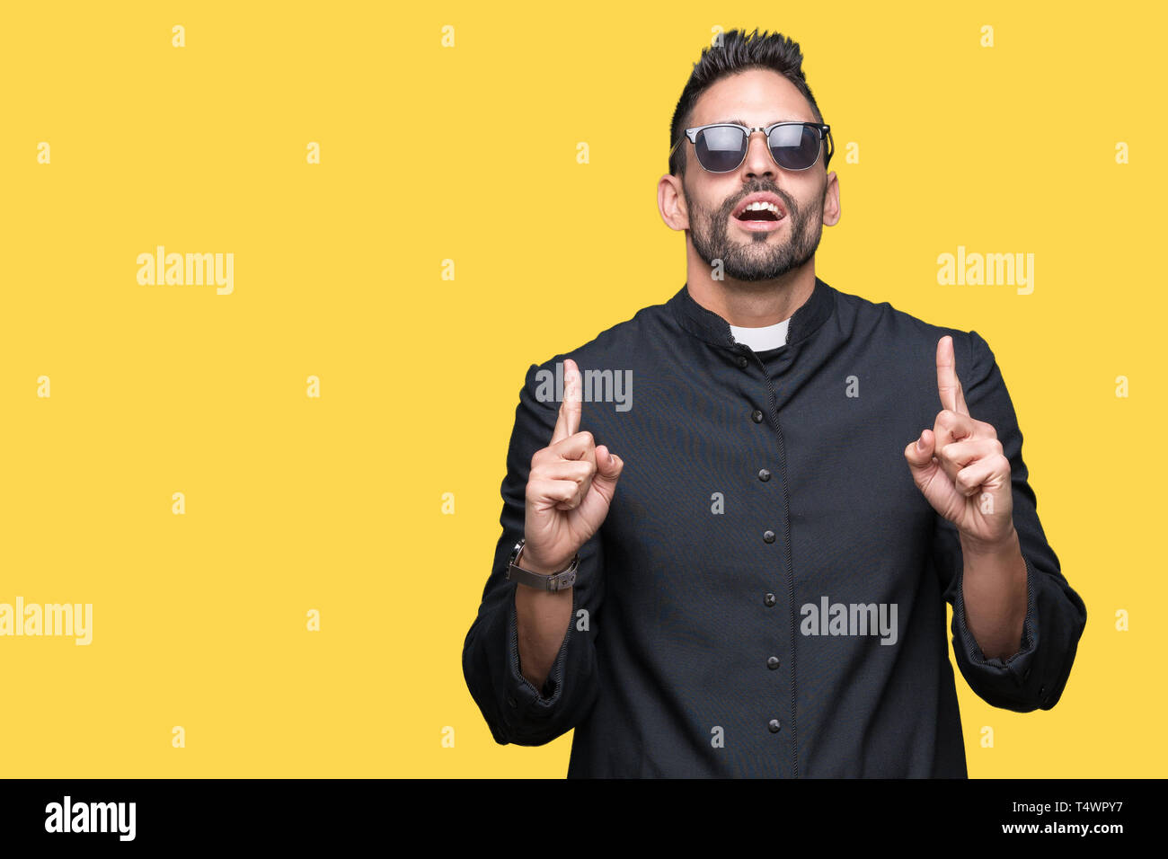 Young Christian priest wearing sunglasses over isolated background ...