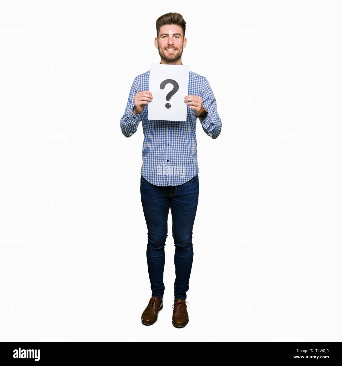 Young handsome man holding paper with question mark with a happy face ...