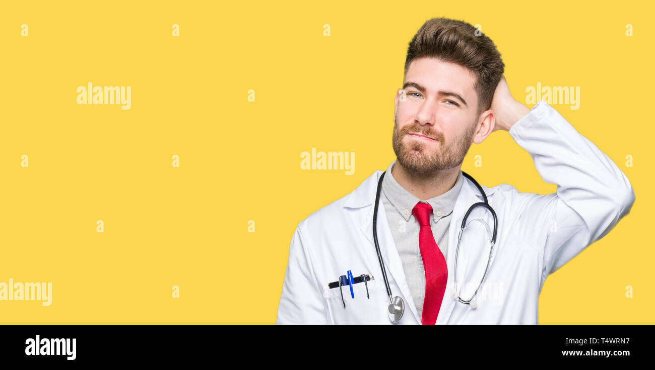 Young handsome doctor man wearing medical coat confuse and wonder about ...