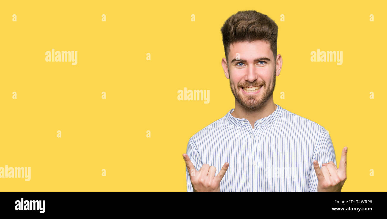 Young handsome man shouting with crazy expression doing rock symbol ...