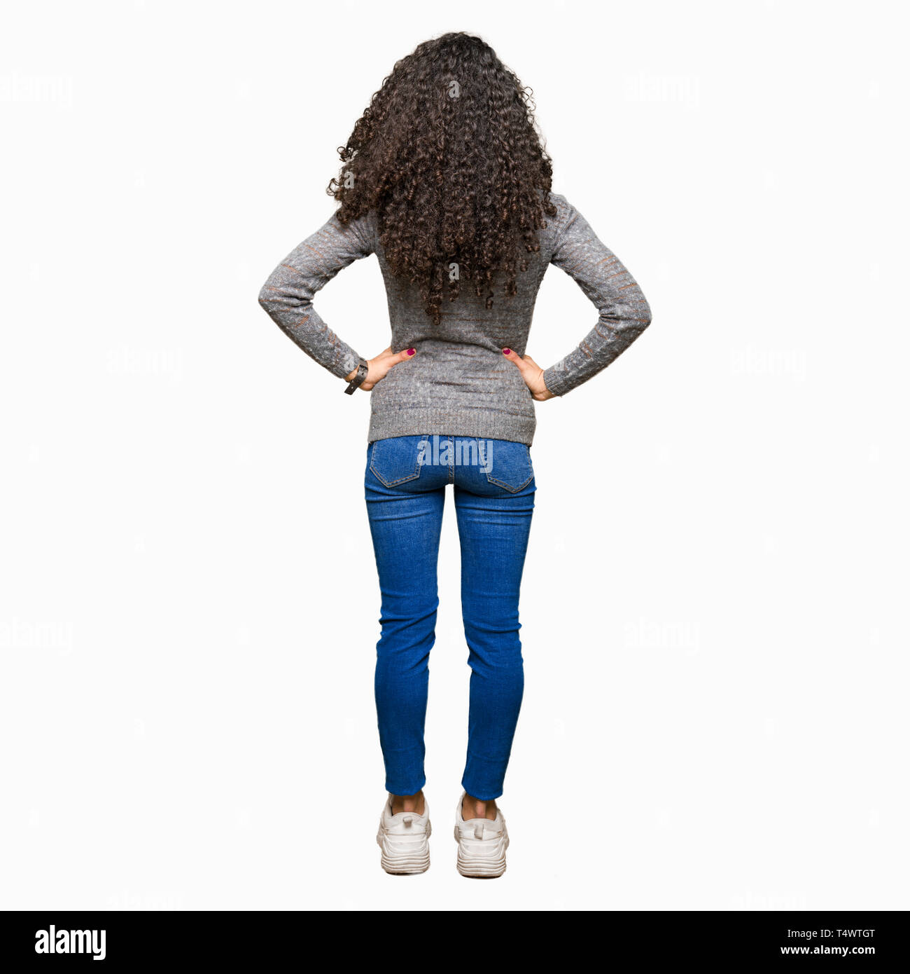 Young beautiful woman with curly hair wearing grey sweater standing ...