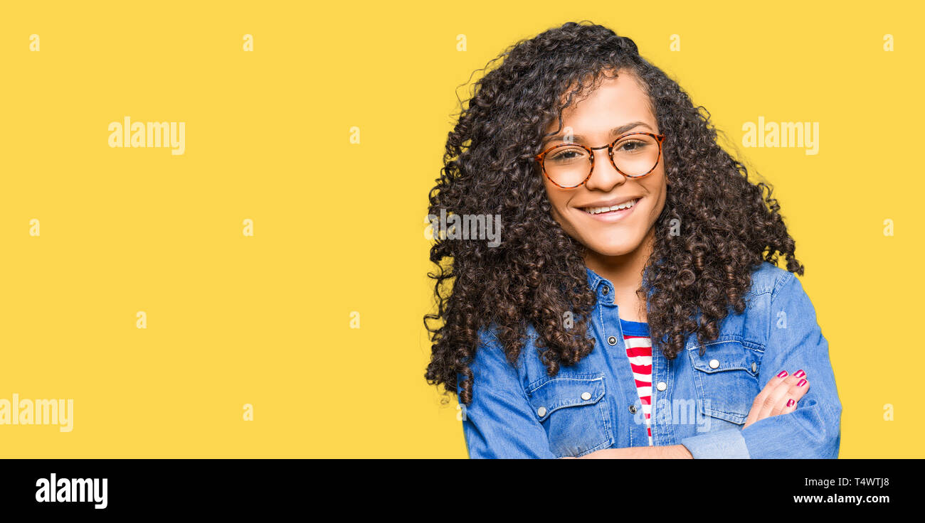 Young beautiful woman with curly hair wearing glasses happy face ...
