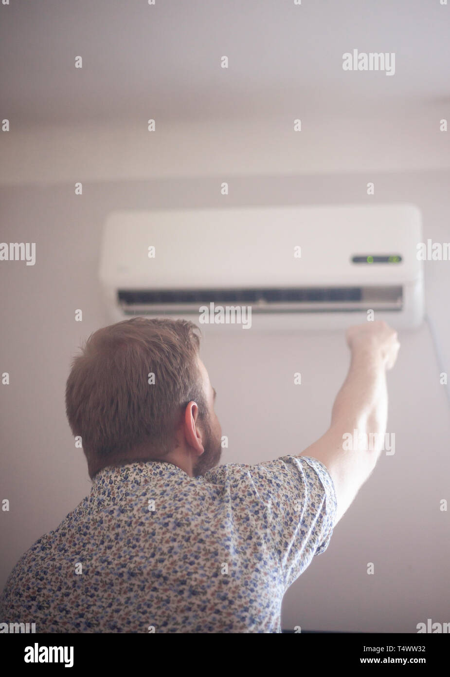 one young man, 20-29 years old, turning on his air conditioner. rear ...