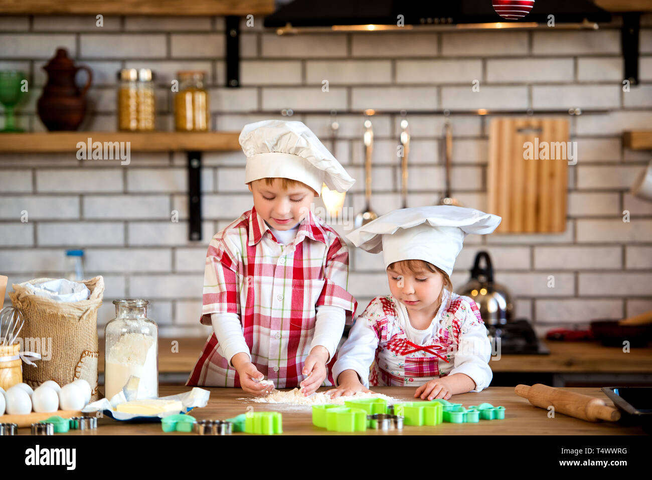 Children brother and sister bake gingerbread in the kitchen. A girl and ...