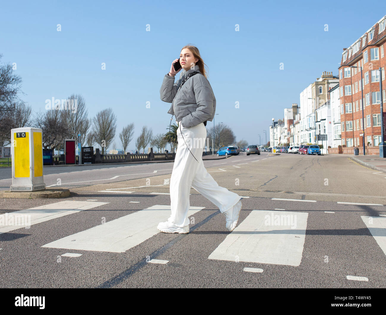 Teenage girl walking across a zebra crossing on her mobile phone Stock ...