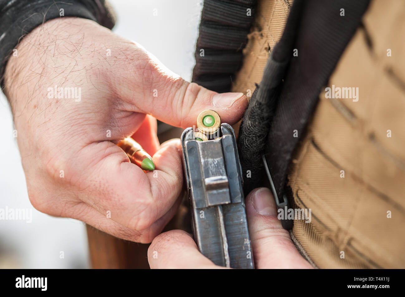 Close-up top macro view of soldier hands load rifle machine gun bullets ...