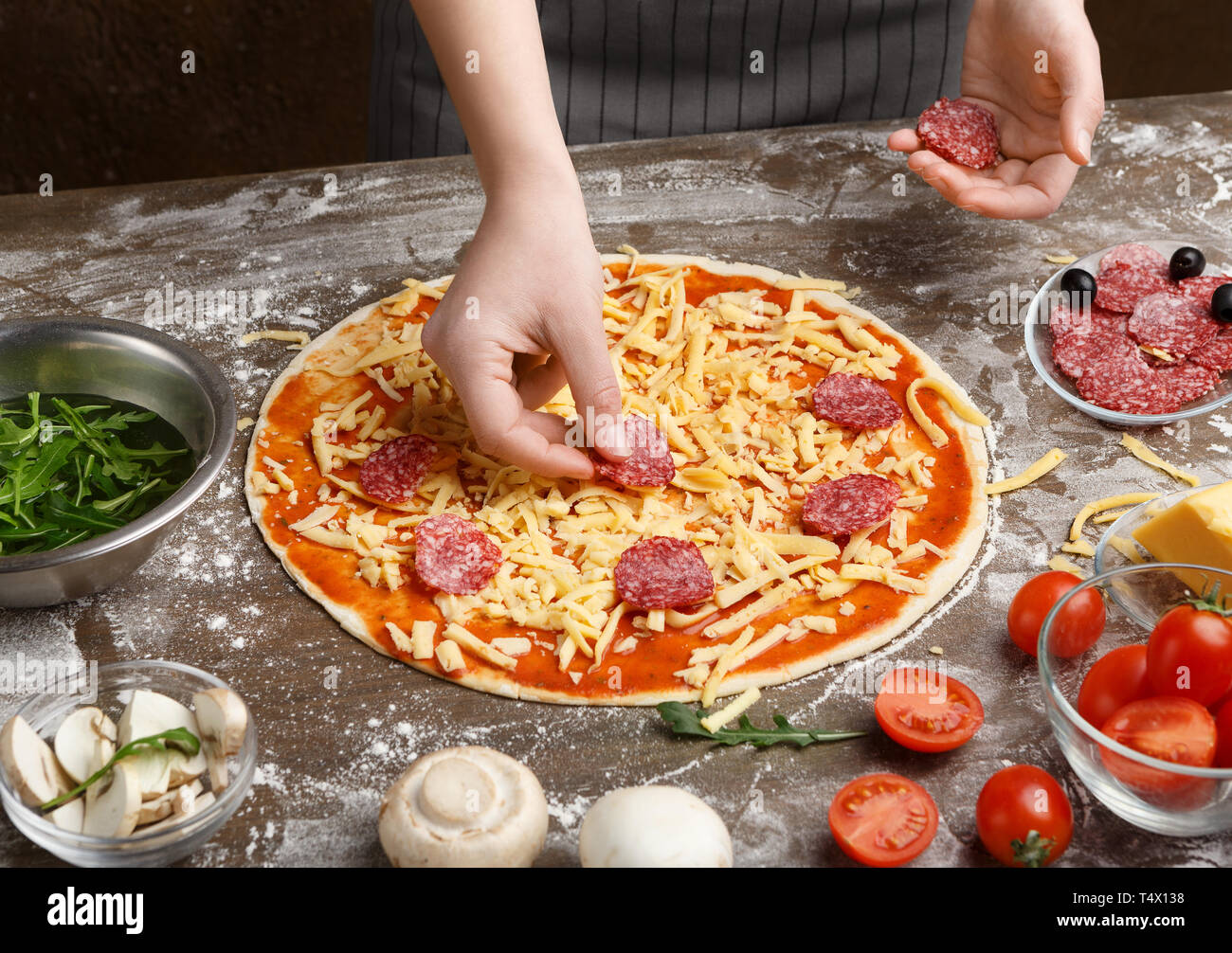 Woman preparing homemade pepperoni pizza, adding salami Stock Photo - Alamy