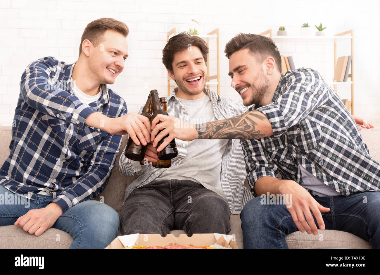 Cheers. Happy friends drinking beer at home Stock Photo - Alamy