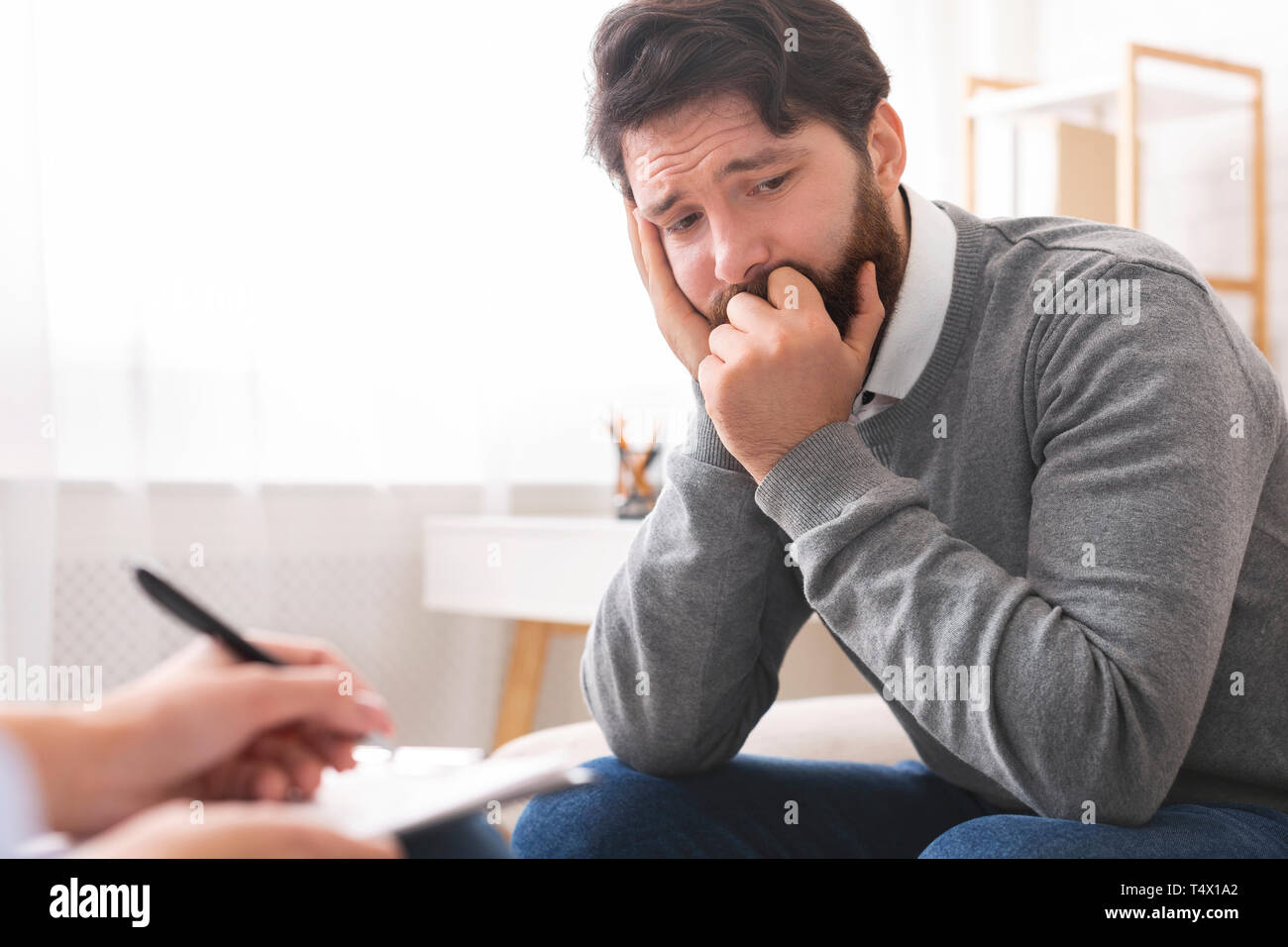 Millennial man with depression during psychotherapy session Stock Photo ...