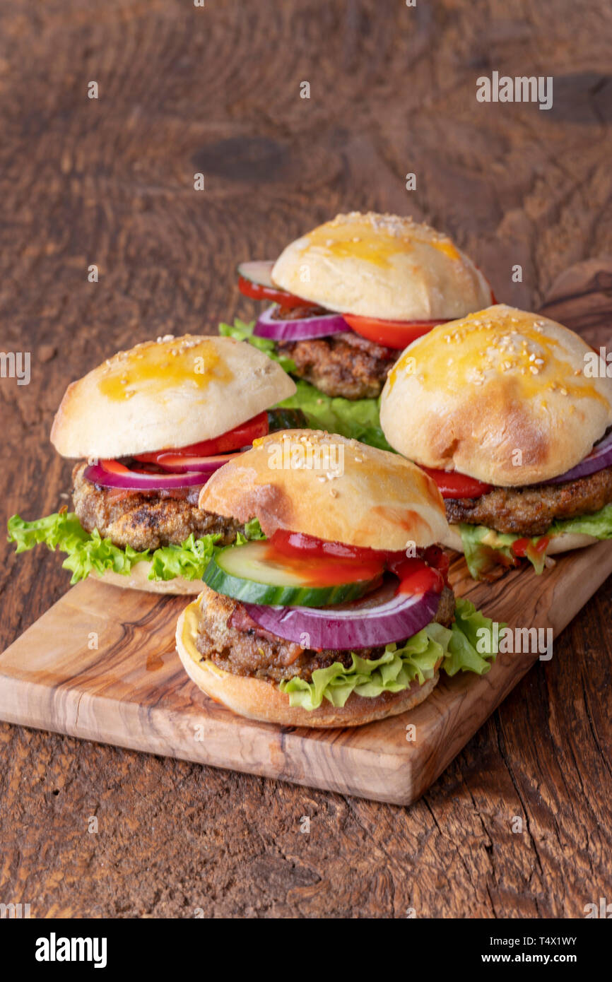 four hamburgers on dark wooden Stock Photo - Alamy