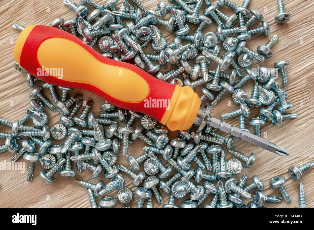 Manual screwdriver screws and dowels on a wood background Stock Photo ...