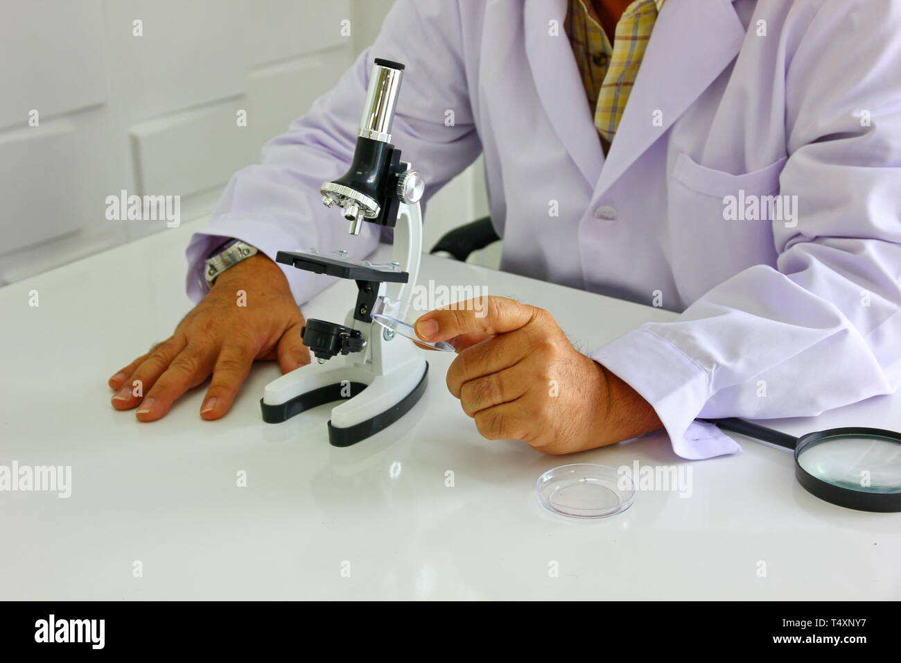 the researcher in white suit with misroscope and looking microscopic ...