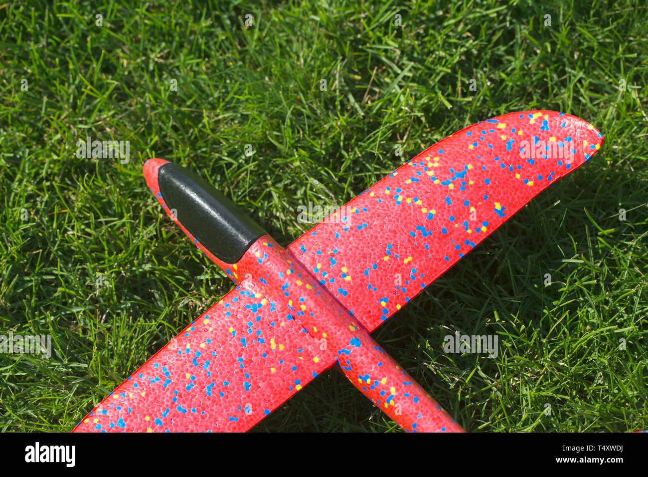 Foam red plane lying on the grass, macro frame from above Stock Photo ...