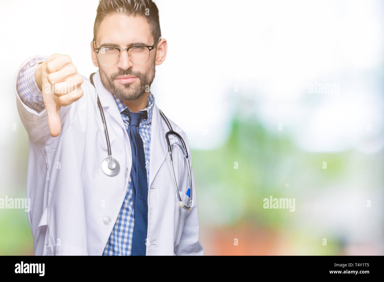 Handsome young doctor man over isolated background looking unhappy and ...