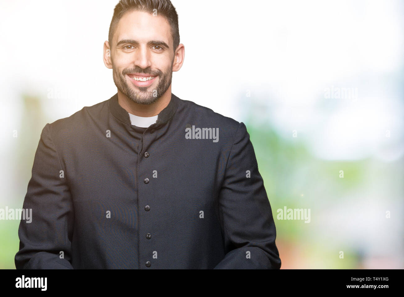 Young Christian priest over isolated background Hands together and ...