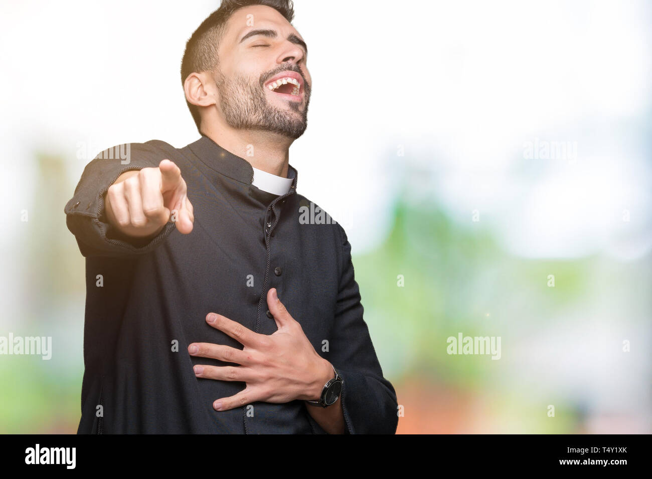 Young Christian priest over isolated background Laughing of you ...