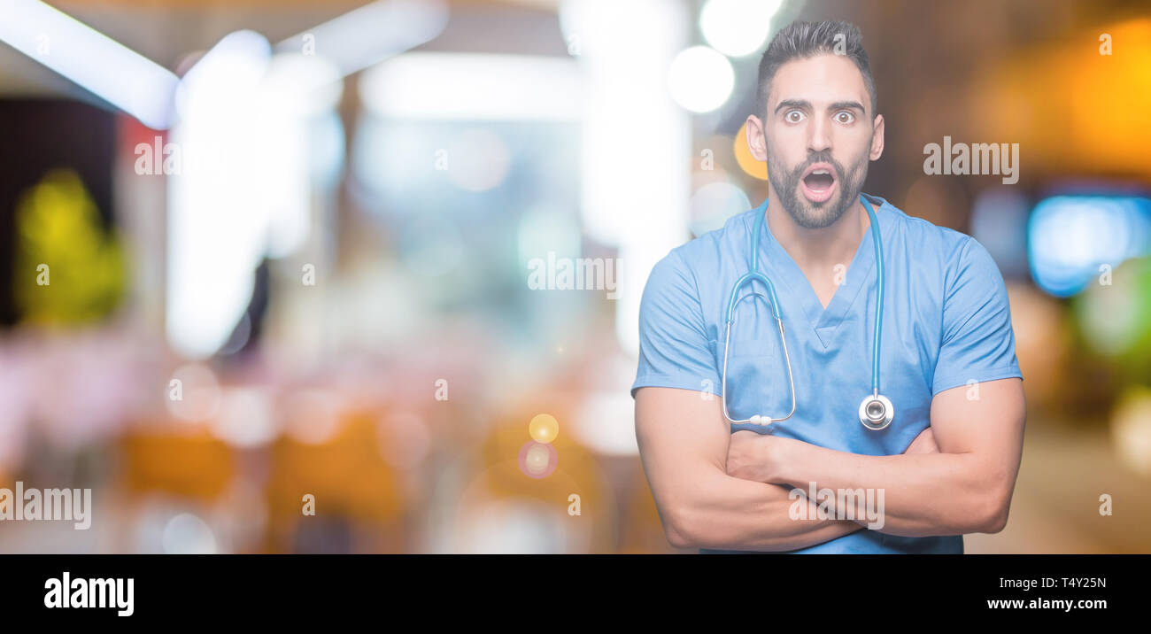 Handsome young doctor surgeon man over isolated background afraid and ...