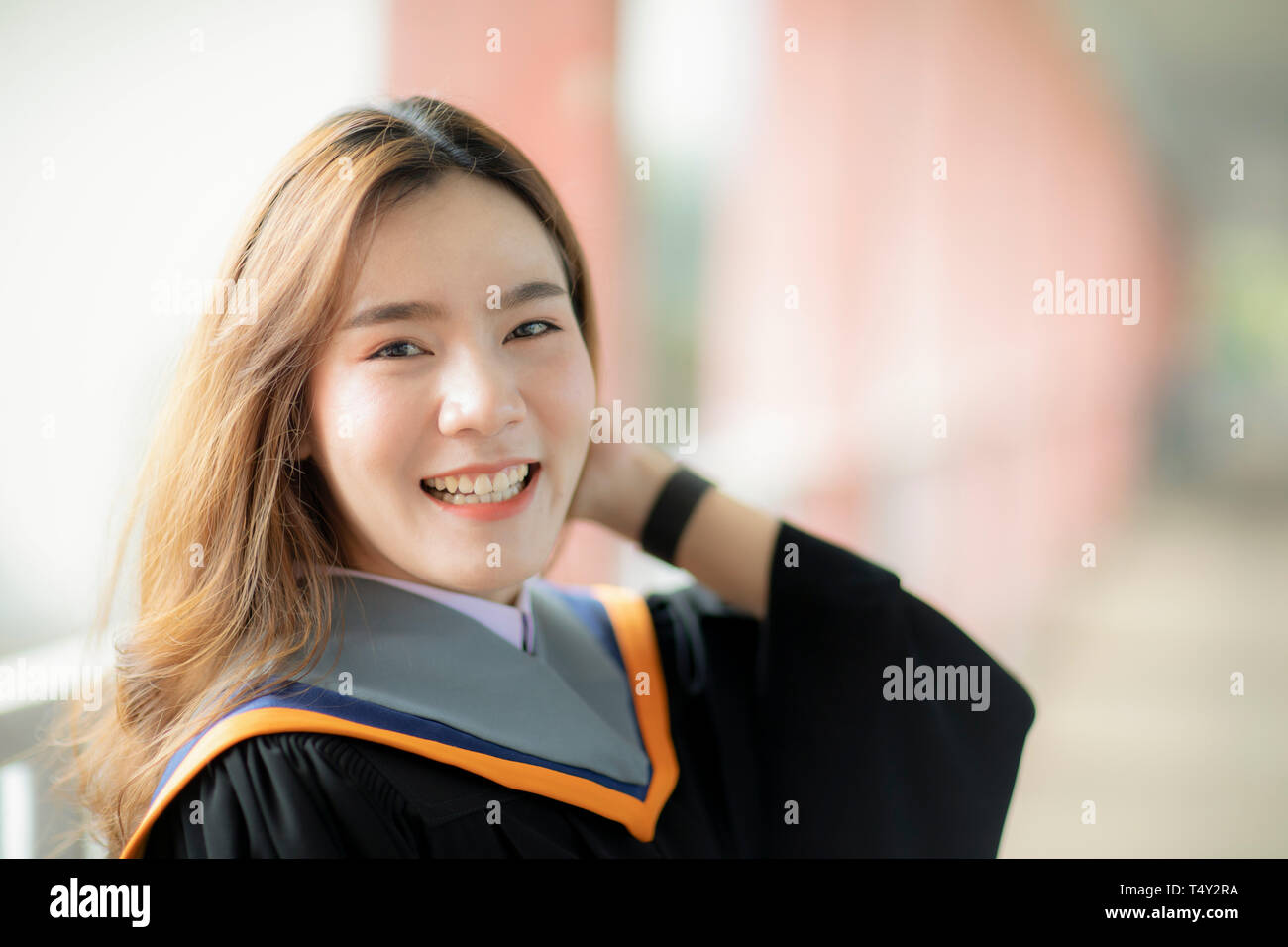 toothy smiling face of beautiful asian younger woman wearing university ...