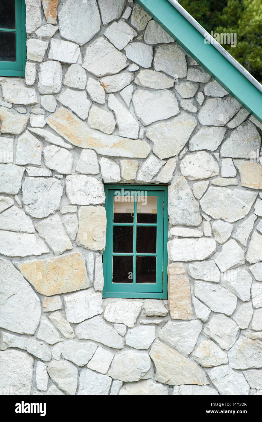 Small wooden window in a stone cottage with green trim and gable, part ...