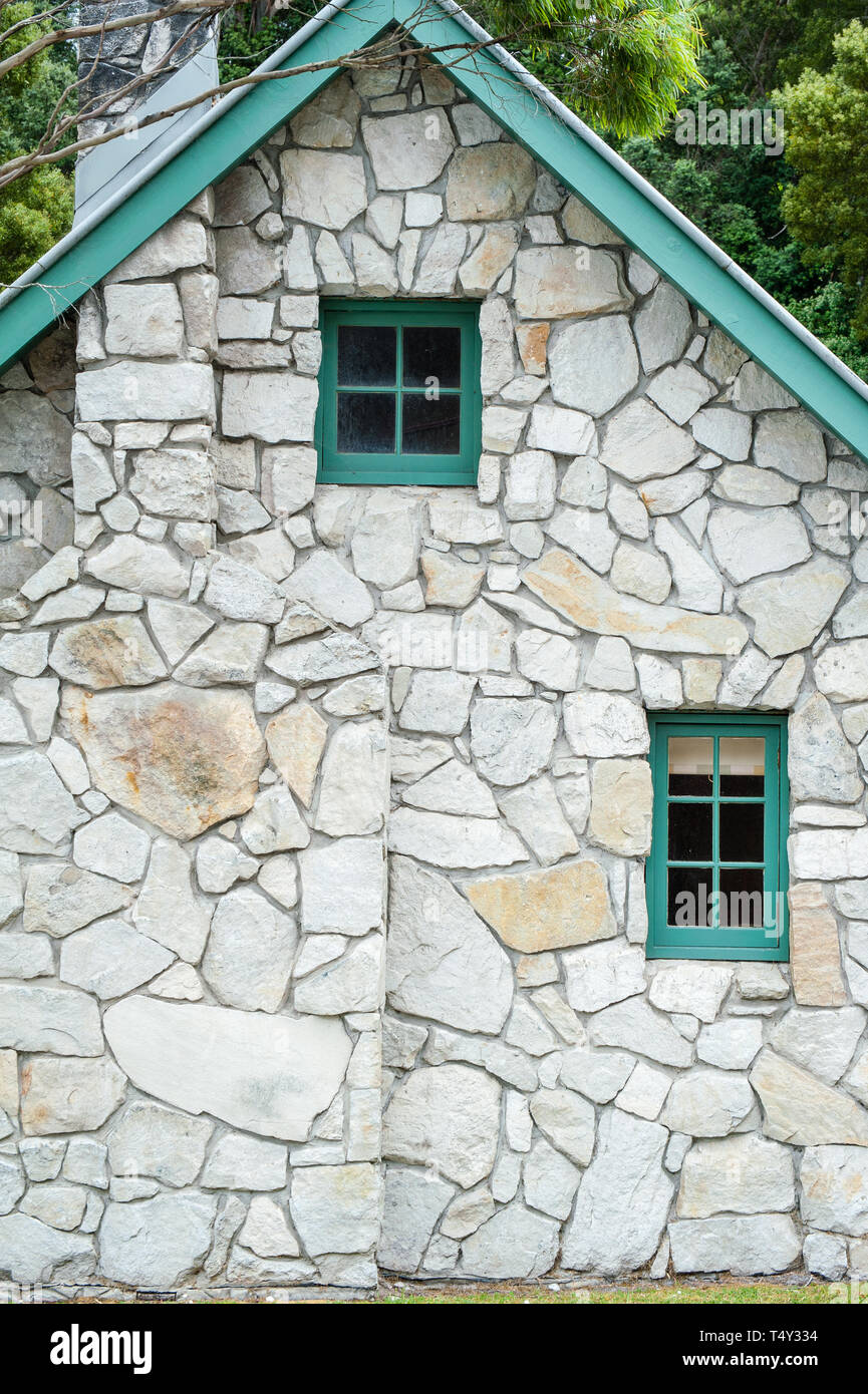 Small wooden windows and chimney stack in a stone cottage with green ...