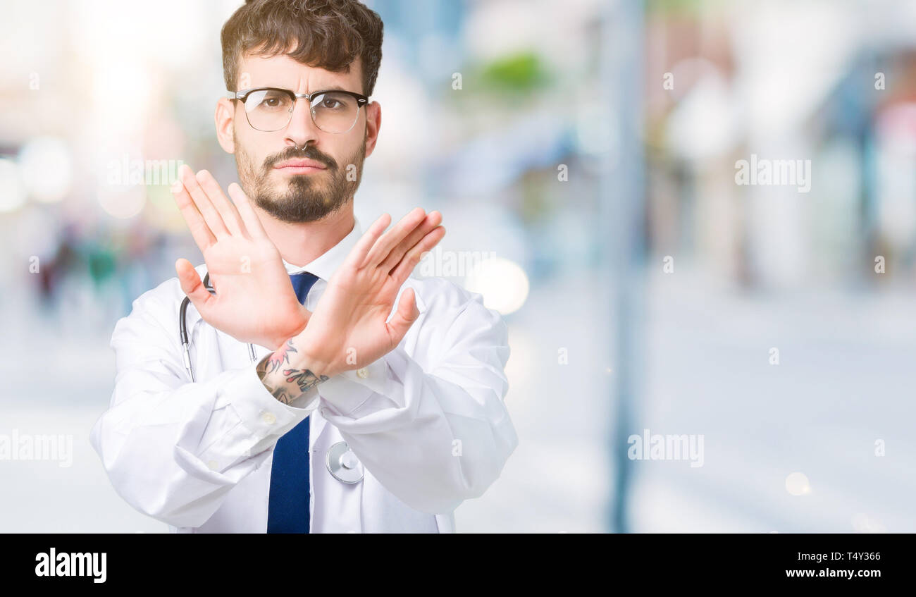 Young doctor man wearing hospital coat over isolated background ...