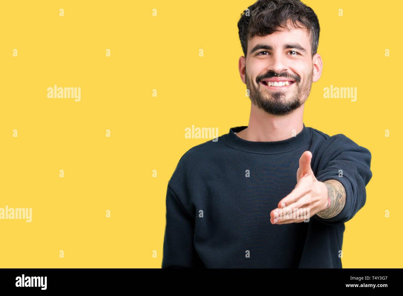 Young handsome man over isolated background smiling friendly offering handshake as greeting and ...