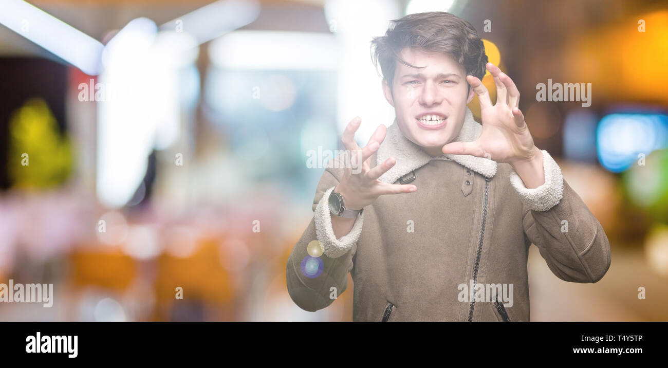 Young handsome man wearing winter coat over isolated background ...