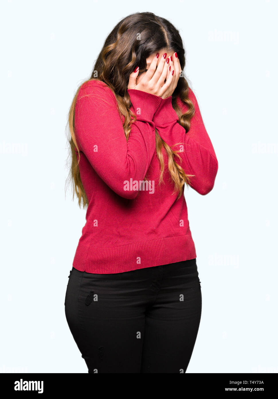 Young beautiful woman wearing red sweater with sad expression covering ...