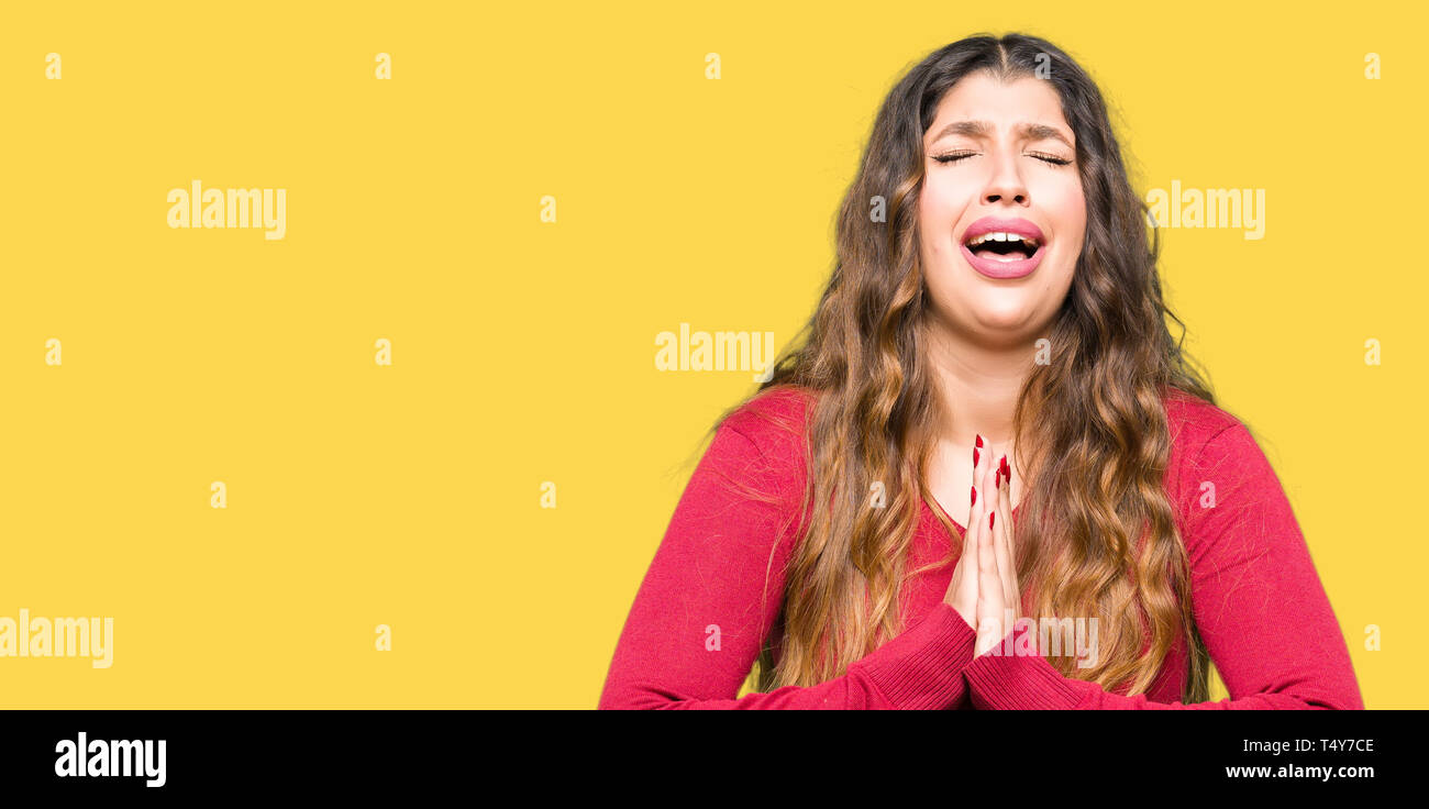 Young beautiful woman wearing red sweater begging and praying with ...