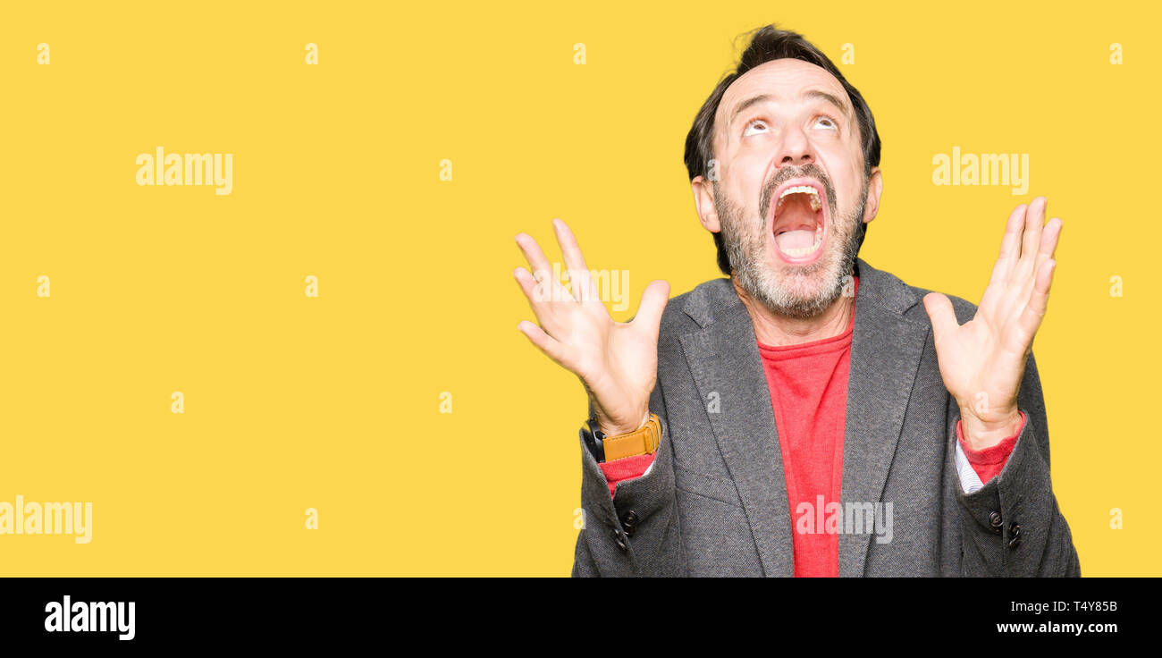 Middle age handsome business man crazy and mad shouting and yelling ...