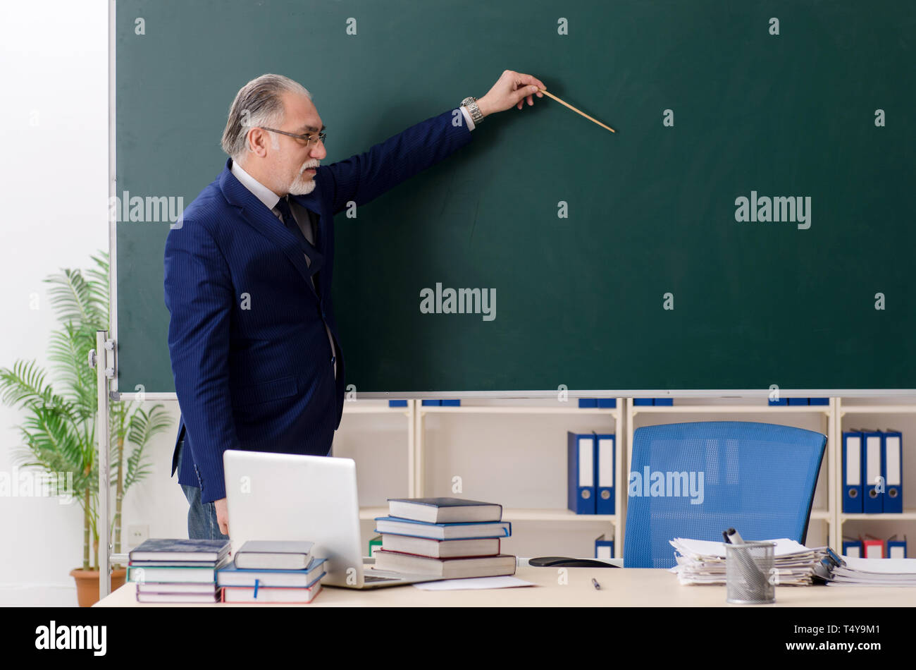 Aged male teacher in front of chalkboard Stock Photo - Alamy