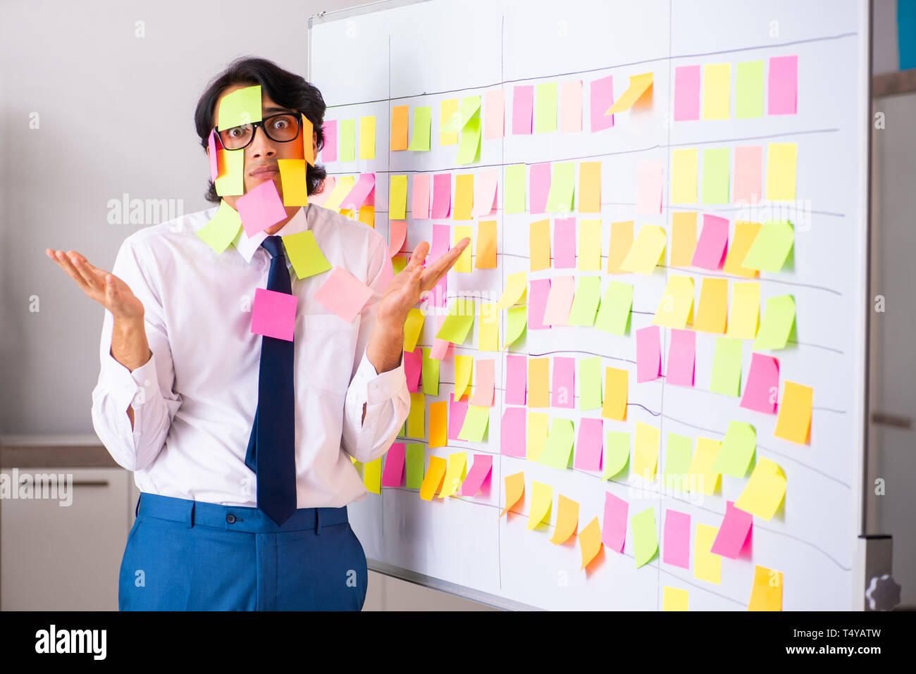 Young employee in conflicting priorities concept Stock Photo - Alamy