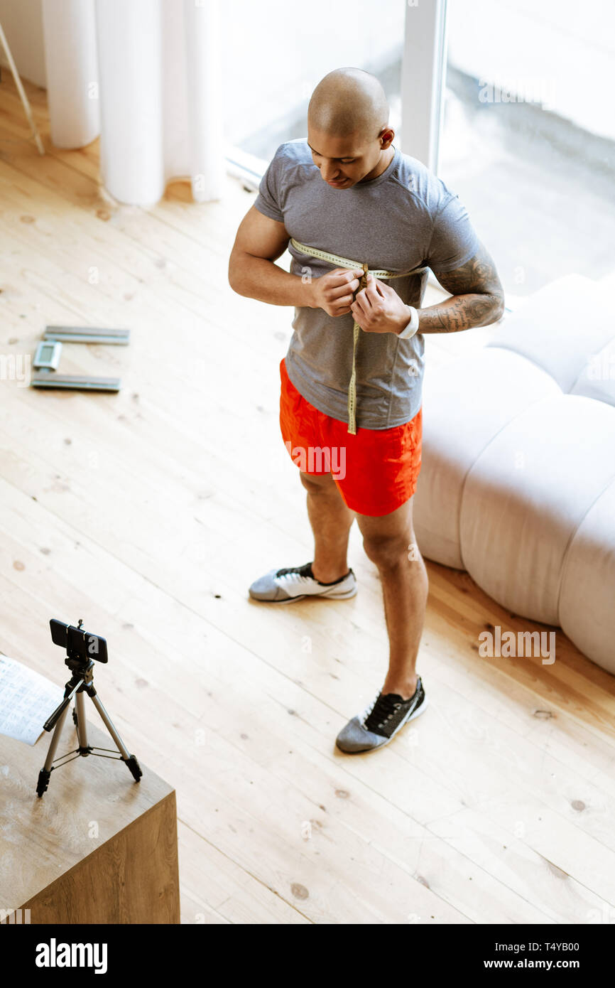 Top view of bodybuilder measuring chest while filming video Stock Photo ...