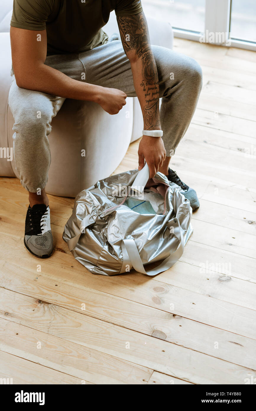 Sportsman wearing grey sport trousers packing his bag for gym Stock ...
