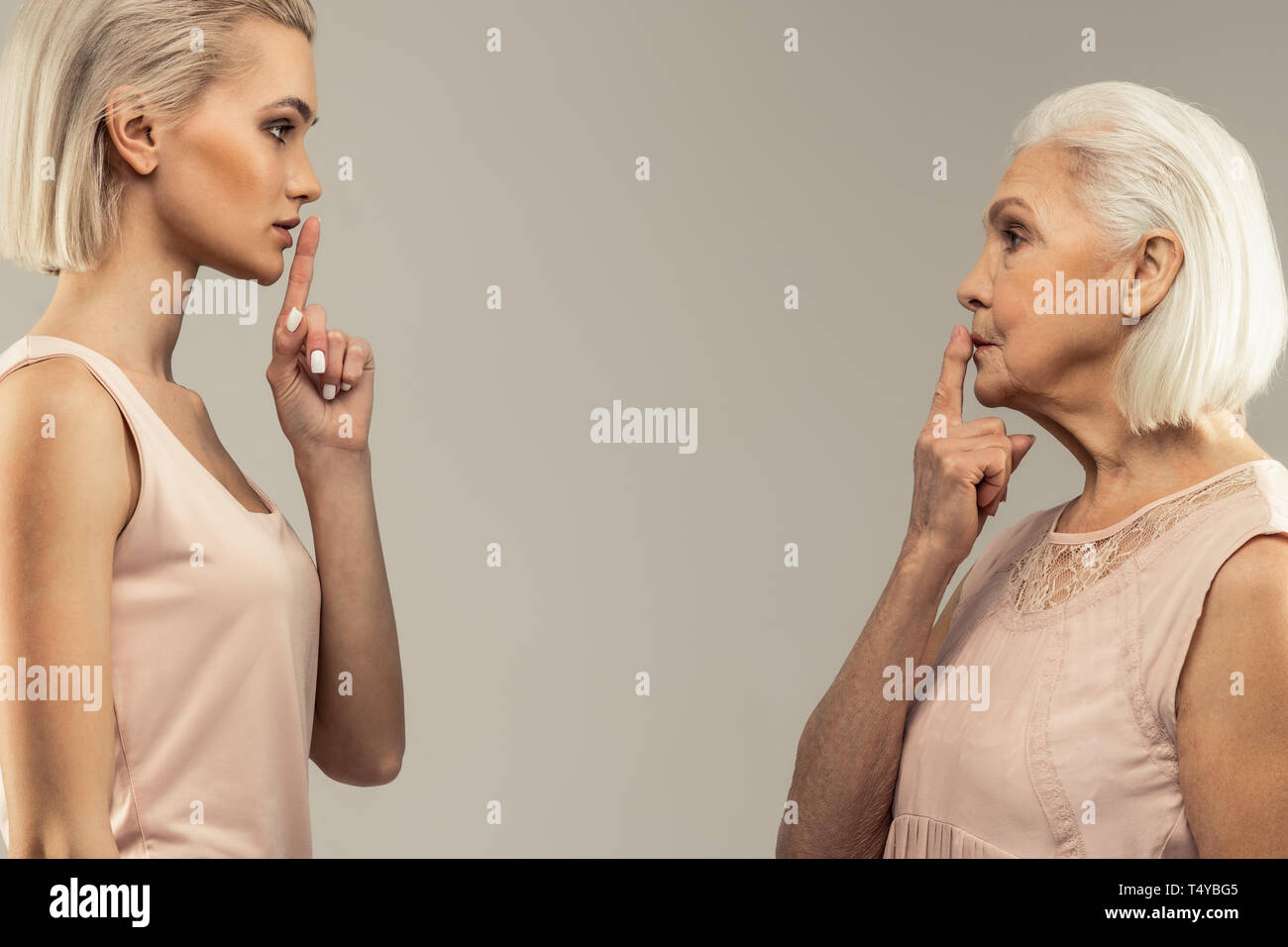 Nice serious women putting their fingers to the lips Stock Photo - Alamy