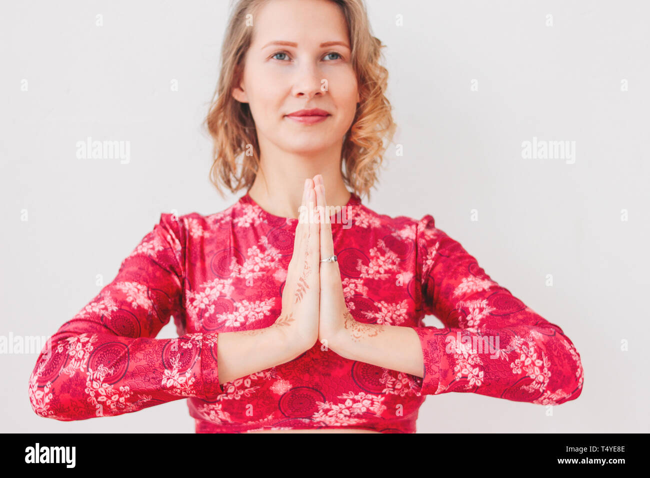 Beautiful young blonde smiling woman in red ethnic costume practicing ...
