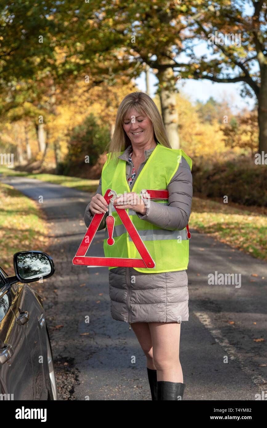 Female motorist putting out a reflective safety triangle following a ...