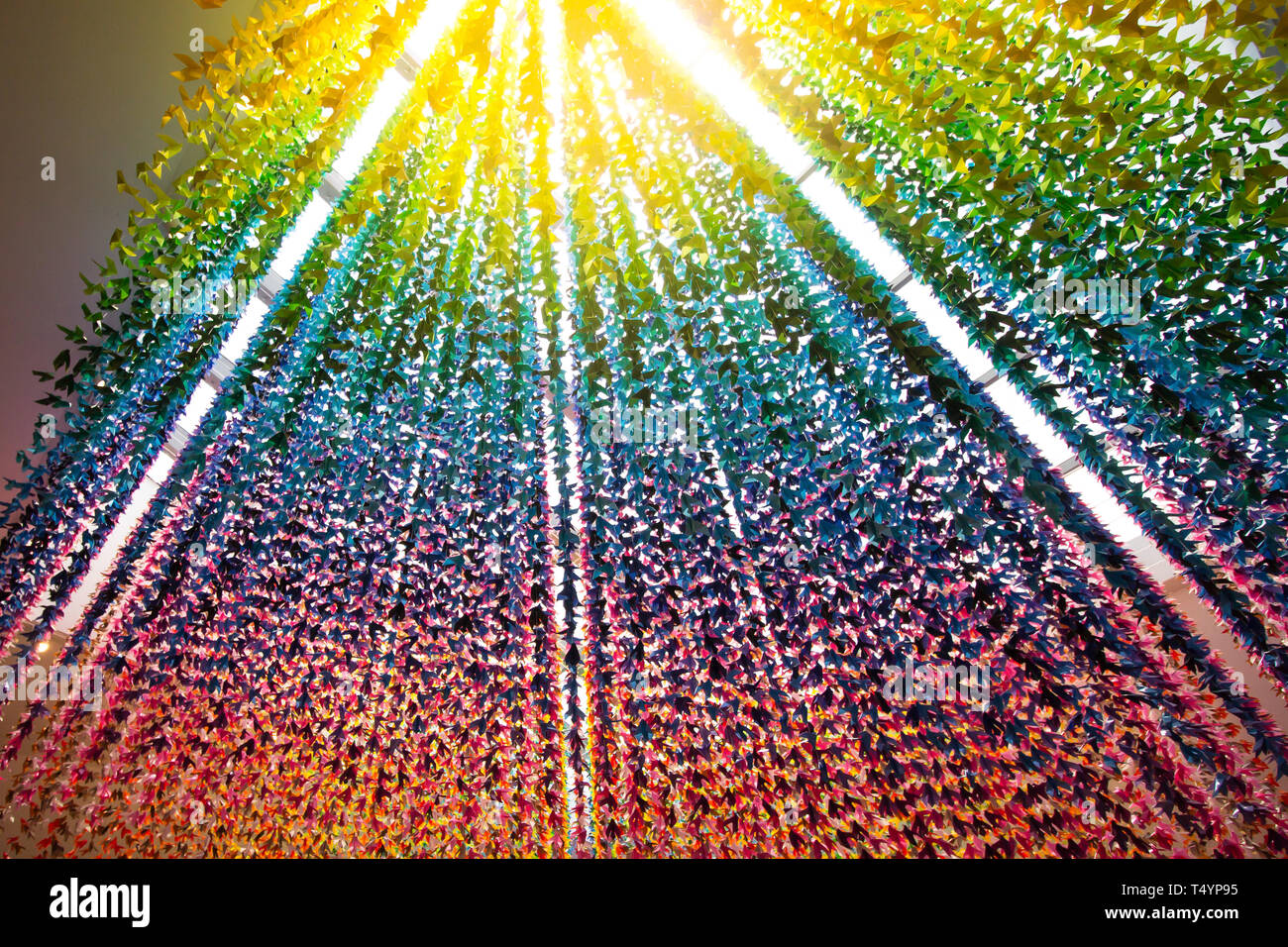 Colorful paper birds hanging together on sunlight through window ...