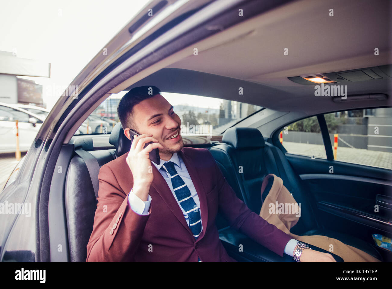 Happy businessman is having a conversation on mobile while driving in a ...