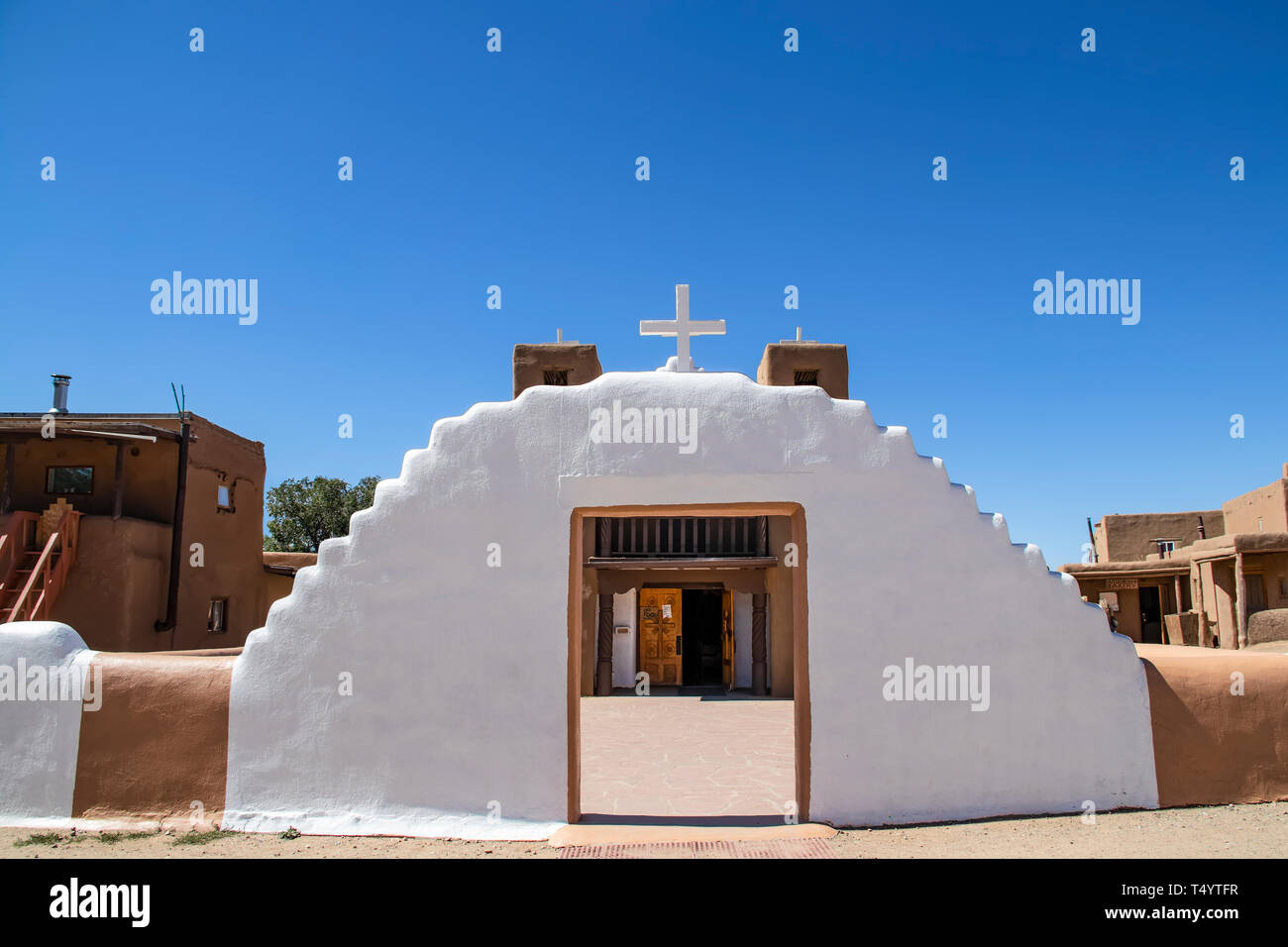 Adobe mud pueblo mission church with gate to plaza courtyard painted ...