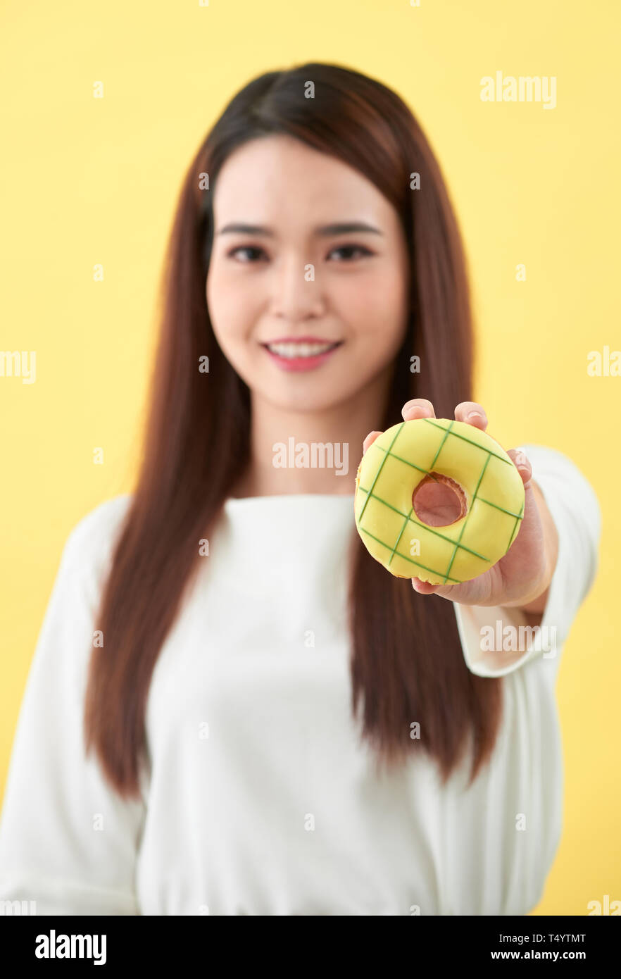 Close up portrait of a cute girl posing with donuts on yellow ...