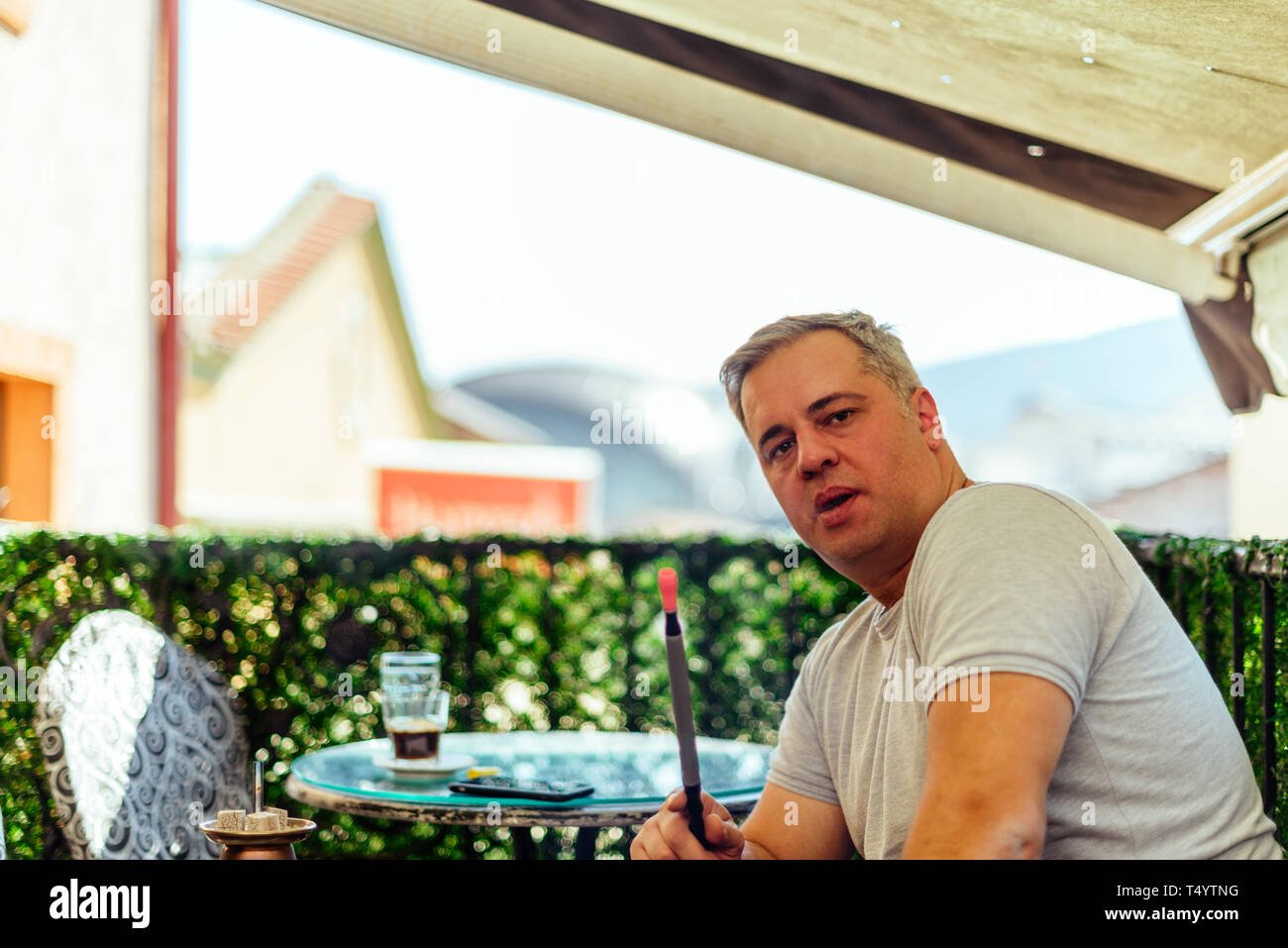 Senior businessman drinking coffee and smoking nargile in nargile bar ...