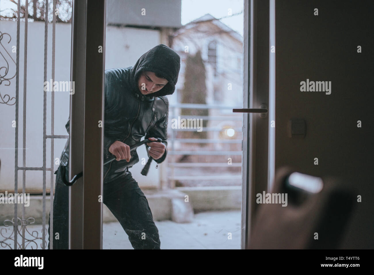 Robbery guy with crowbar trying to open door from the house Stock Photo ...