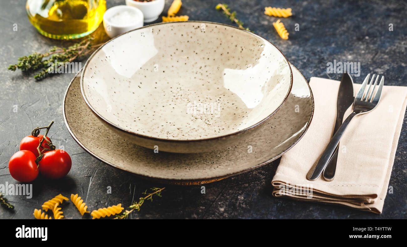 Table setting with cutlery, pasta Fusilli, tomatoes and herbs on dark ...