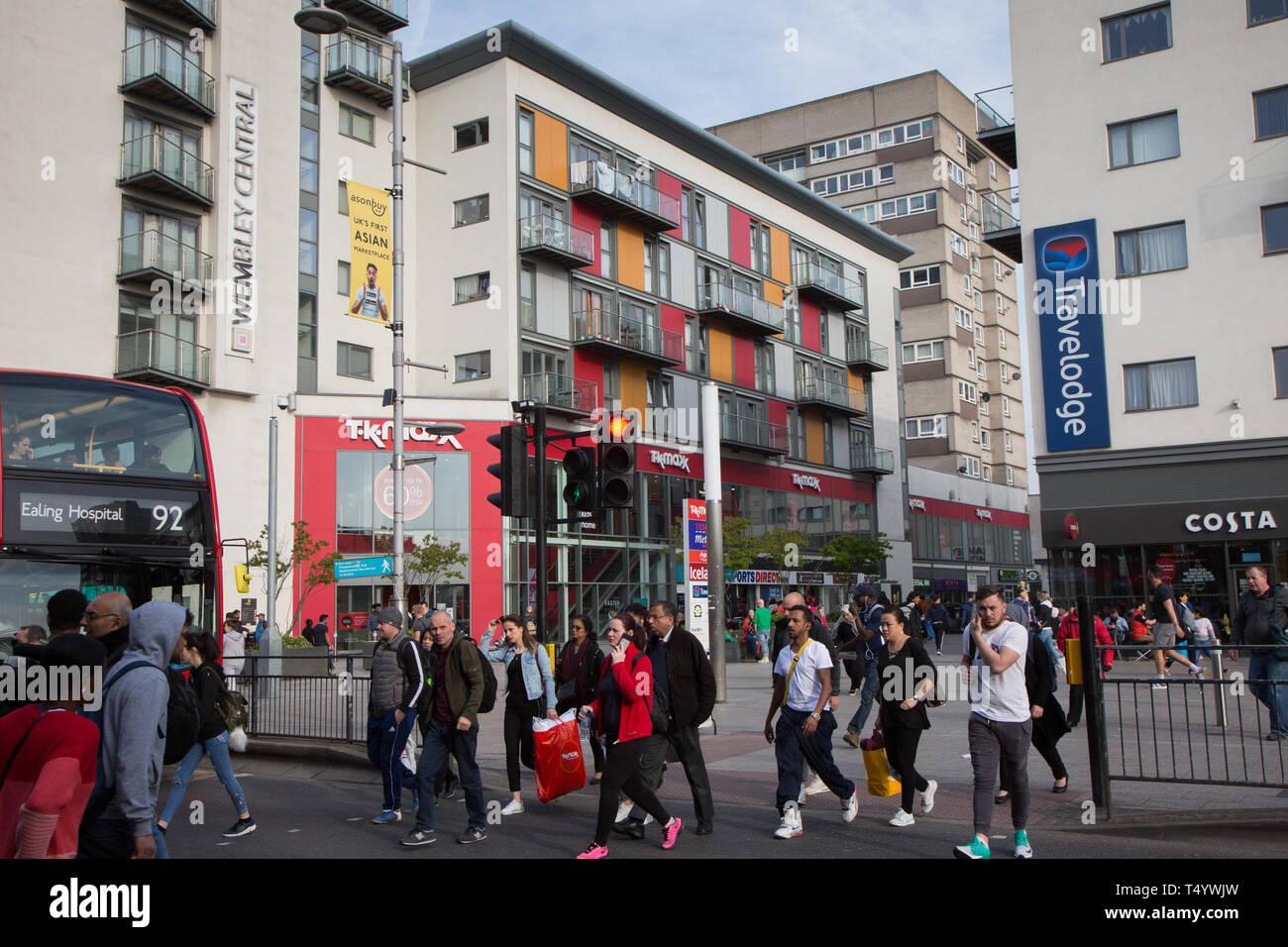 Pedestrians crossing High Road, Wembley, in front of a modern shopping ...